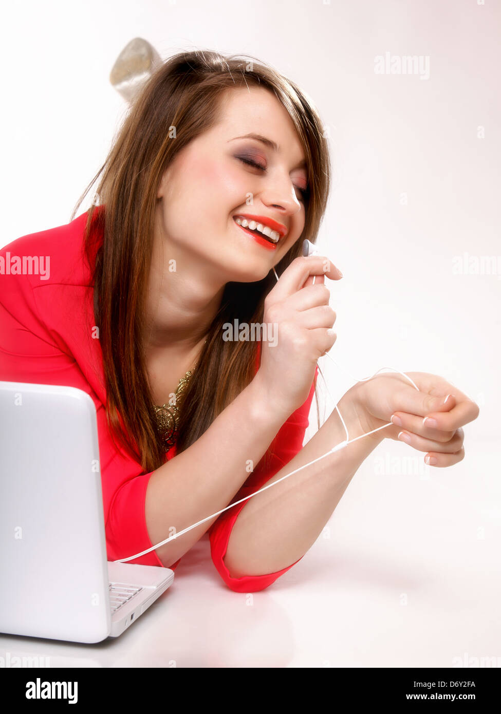 cute girl with headphones listening to music on the laptop on white ...