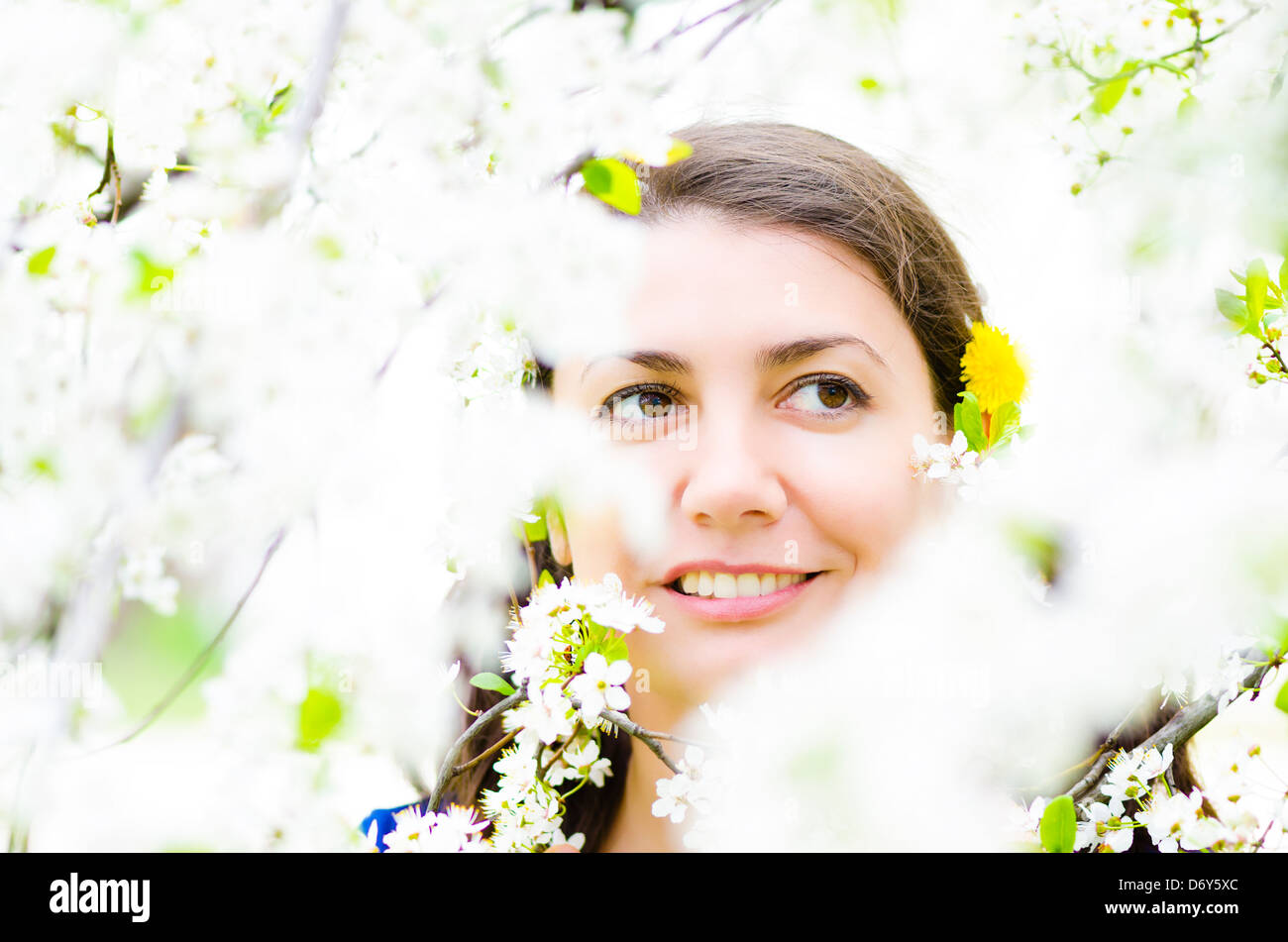 Beautiful young woman looking through blooming trees Stock Photo - Alamy