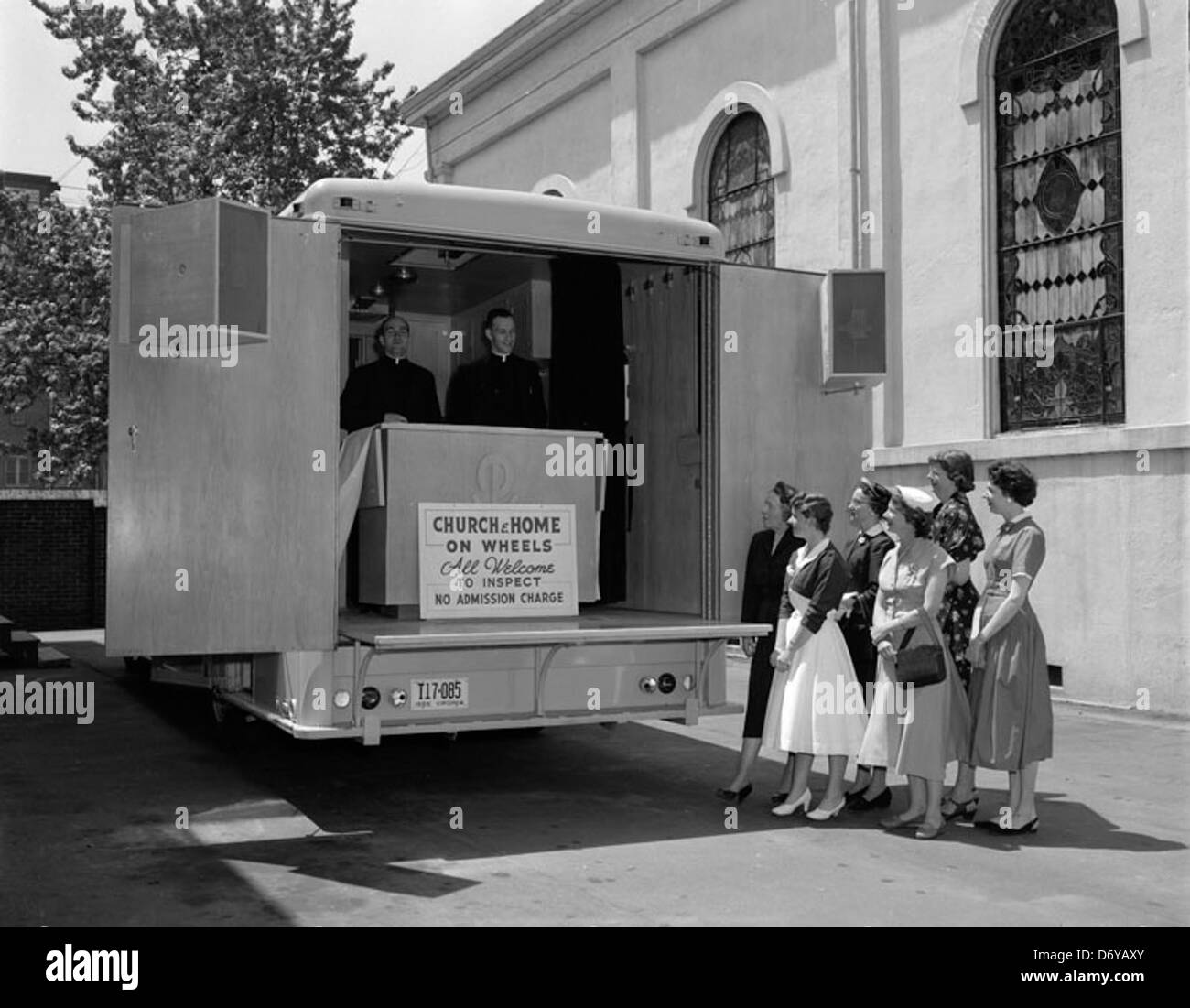 This 1955 photograph shows a mobile Catholic church, a trailer used for ...