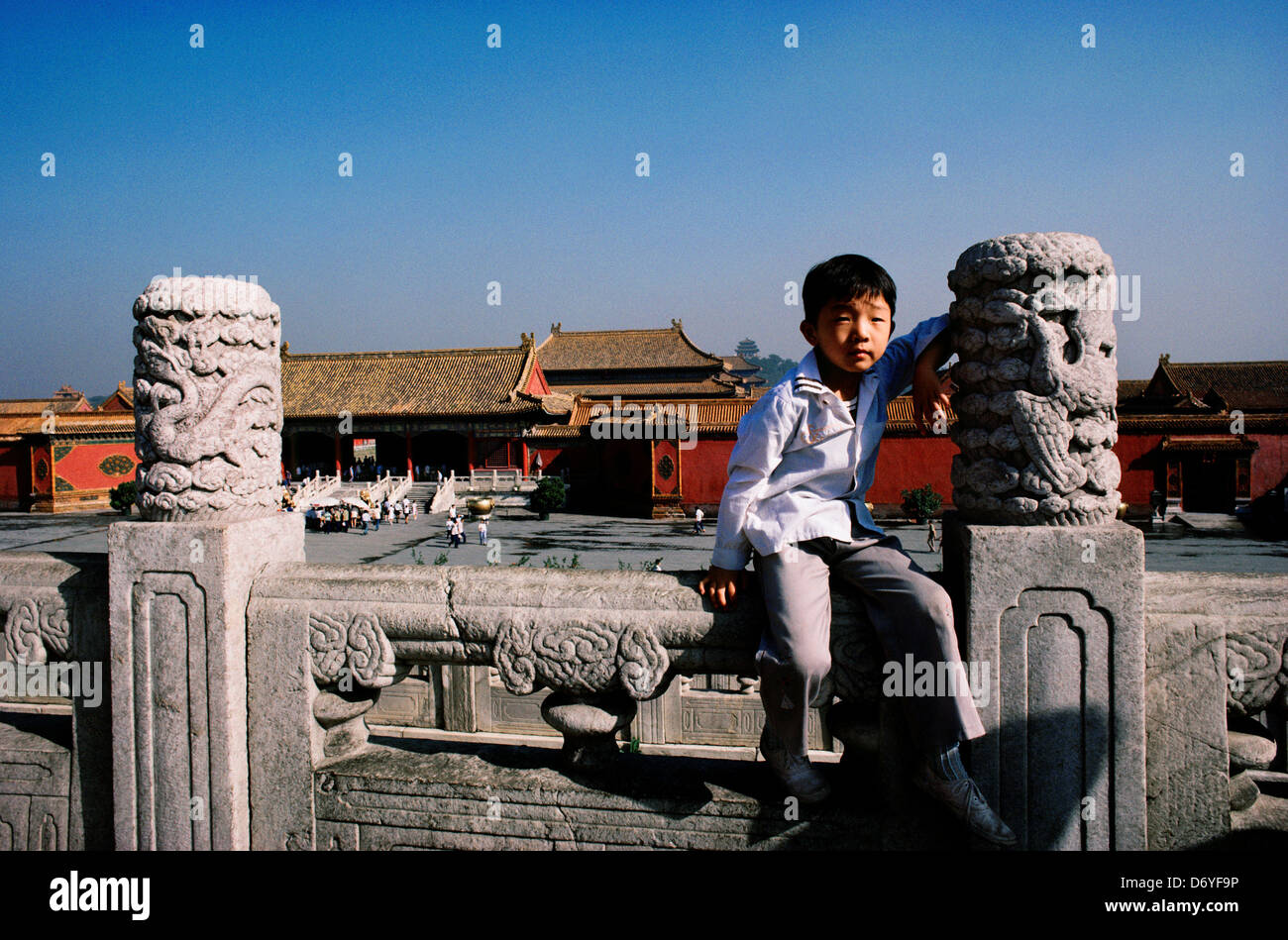 Boy sitting on the stone barricade with a palace in the background ...