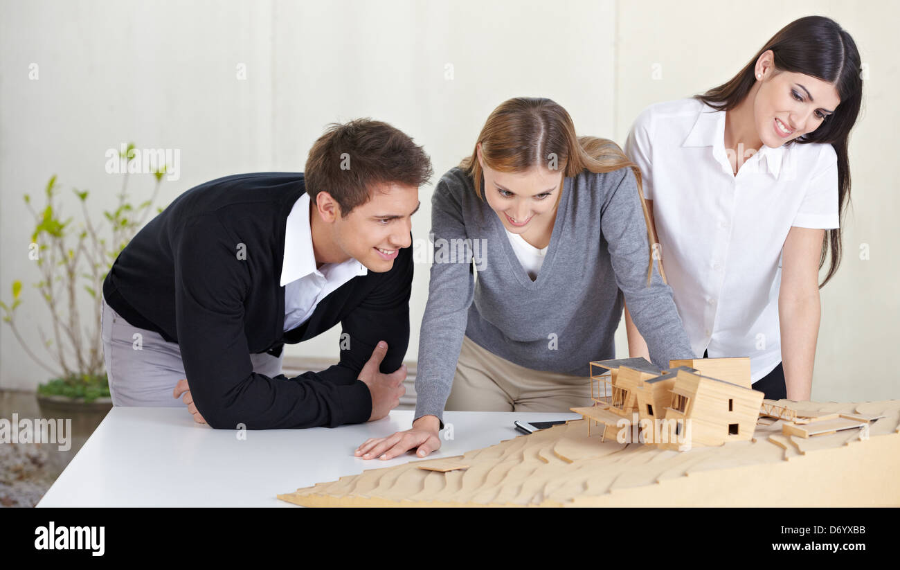 Three architects in office looking at 3D building model Stock Photo - Alamy