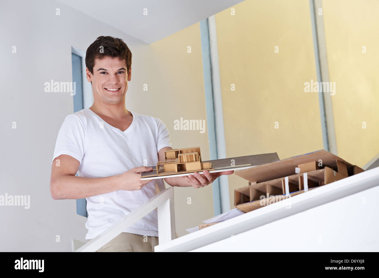Happy architectural student showing building draft made of wood and ...