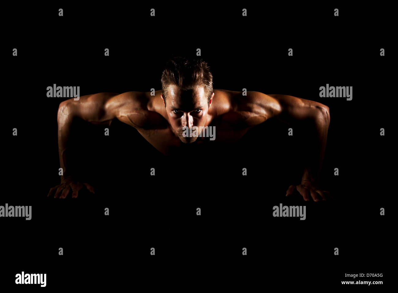 Man with focused eyes doing pushups on black background Stock Photo - Alamy