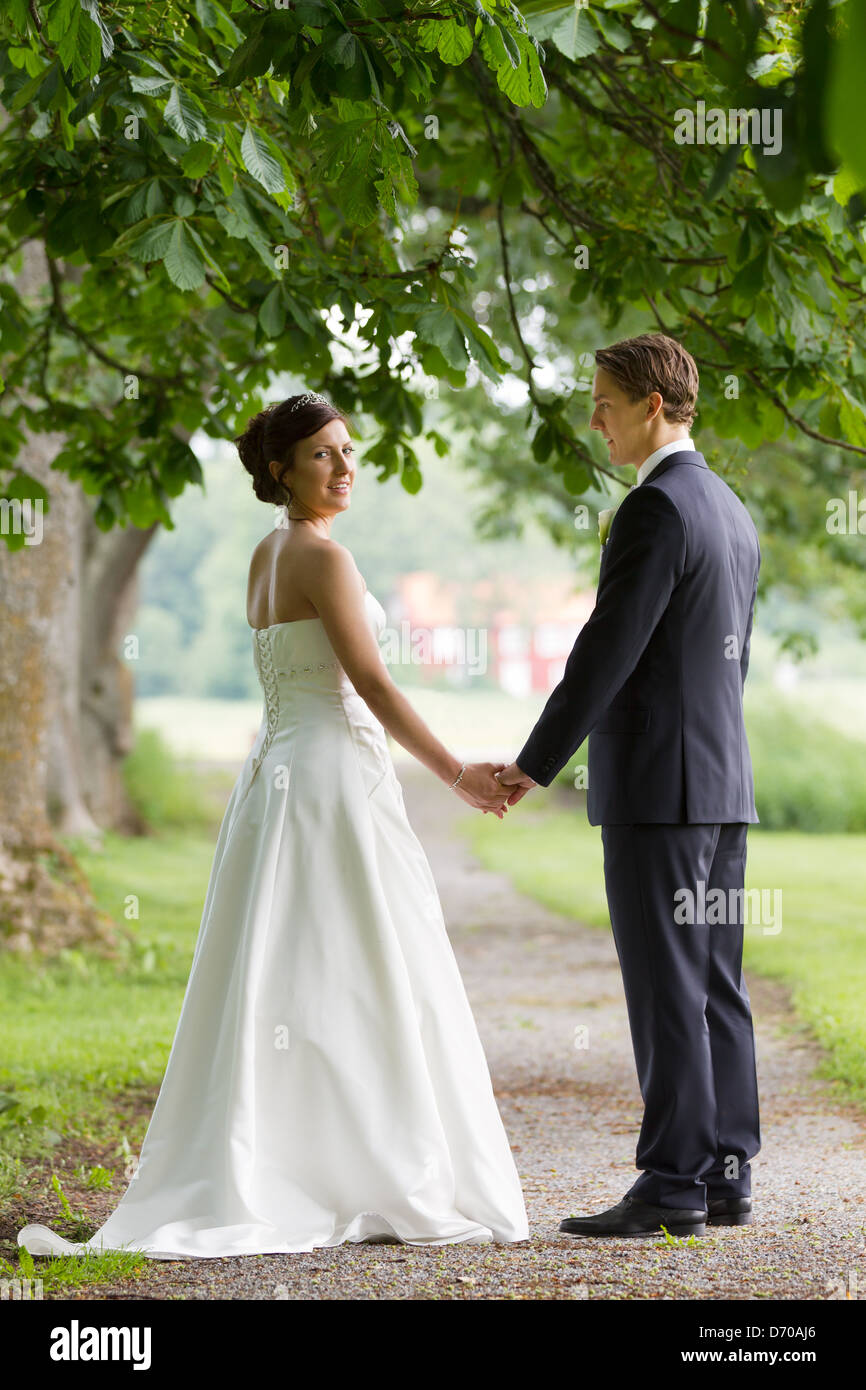 Young couple holding hands and looking back over shoulders at wedding ...
