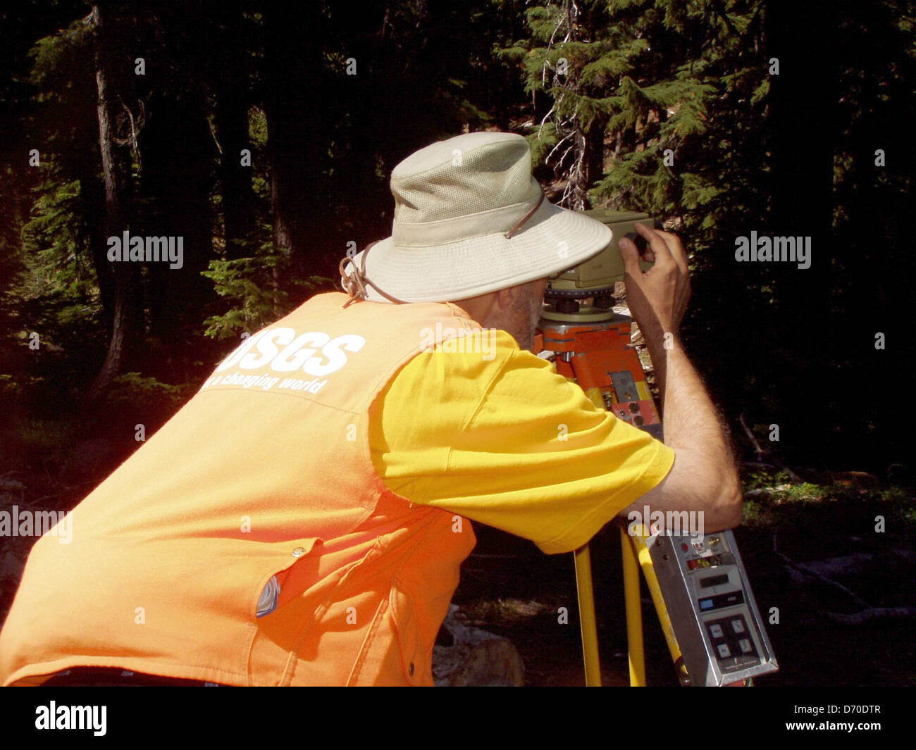 The image shows a USGS surveyor using a leveling gun to measure ...