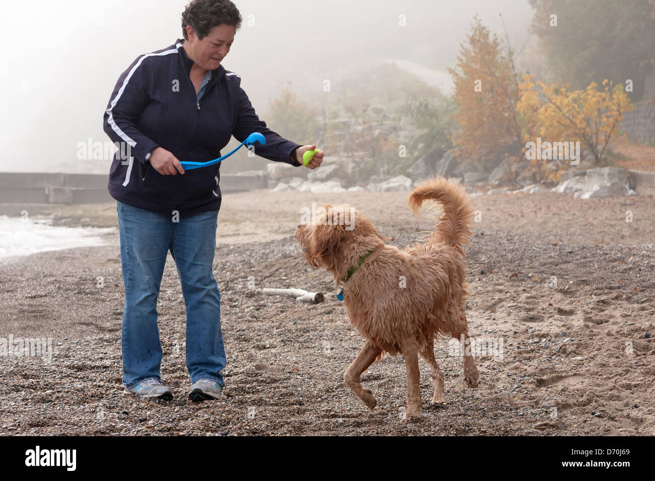 A woman prepares to throw a ball to her dog on a Lake Michigan beach in ...