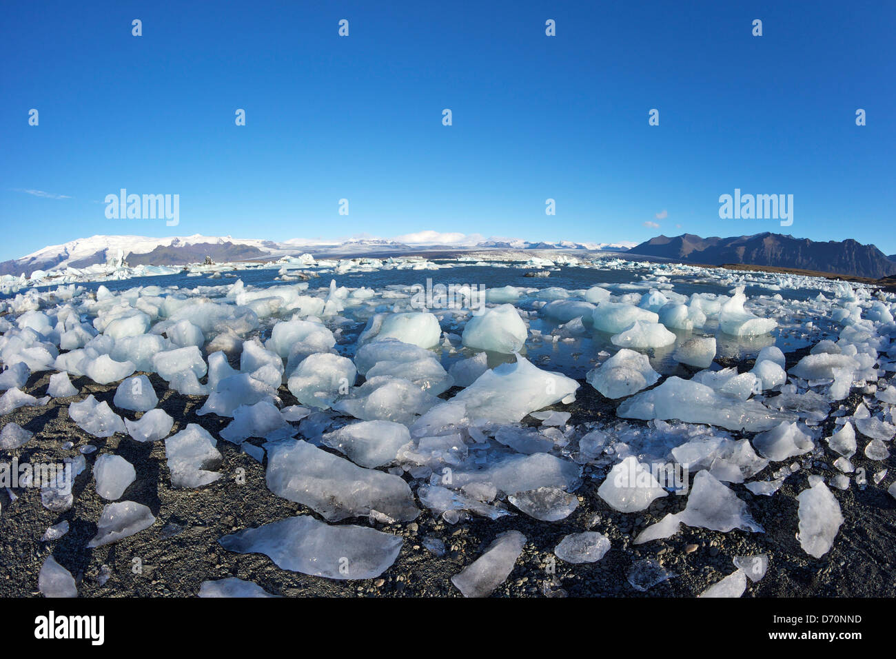 Iceland, Icebergs on glacial lake at Jokulsarlon with snow on massive ...