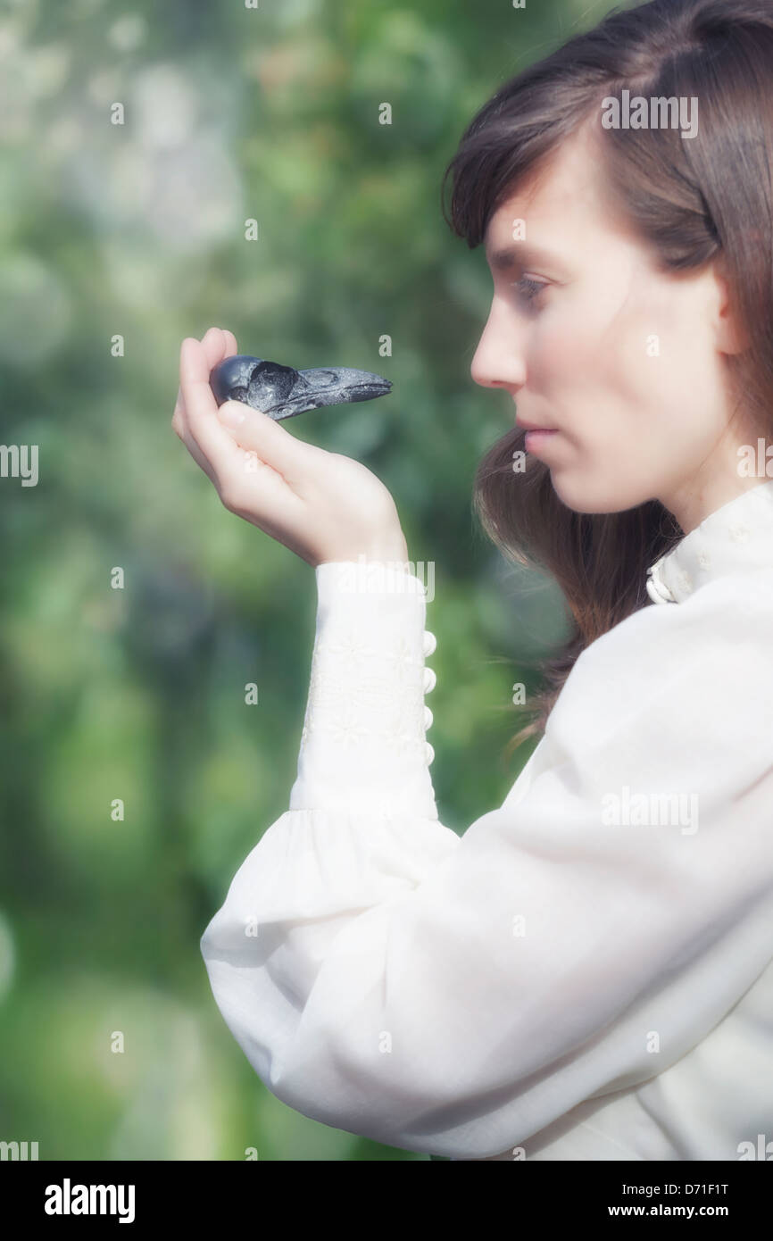 a woman in a vintage dress with the skull of a crow in her hand Stock ...