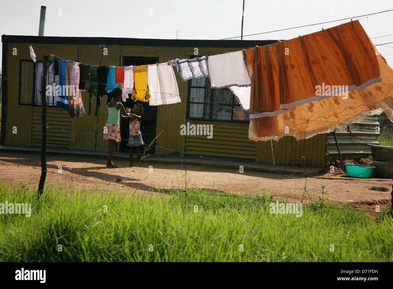 Young African girls play outside their tin shack home Stock Photo - Alamy