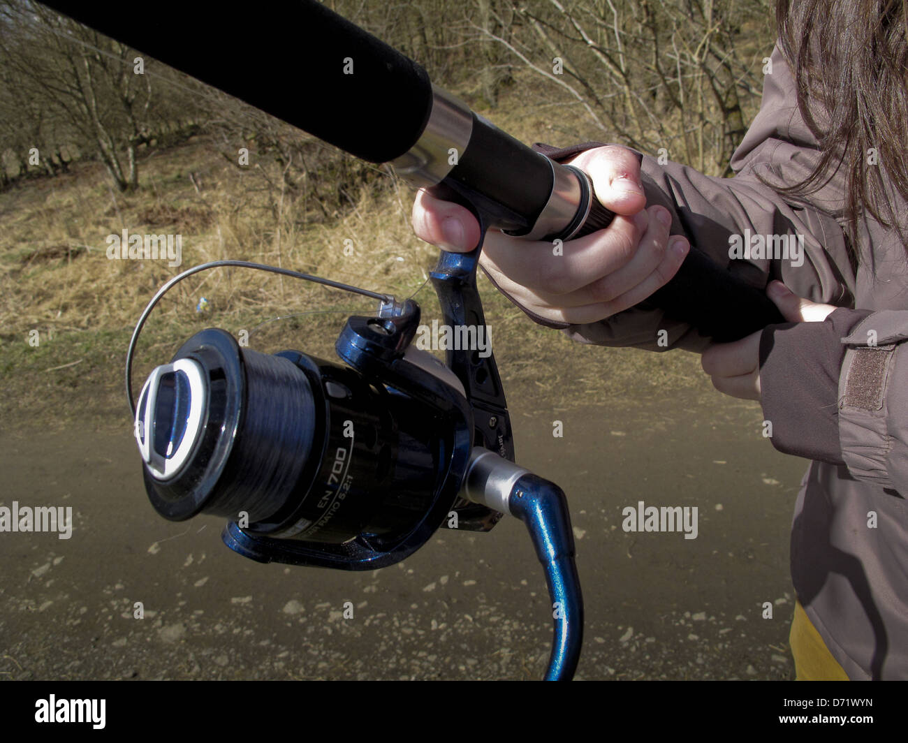 Girl's hand holding fishing rod and reel Stock Photo - Alamy