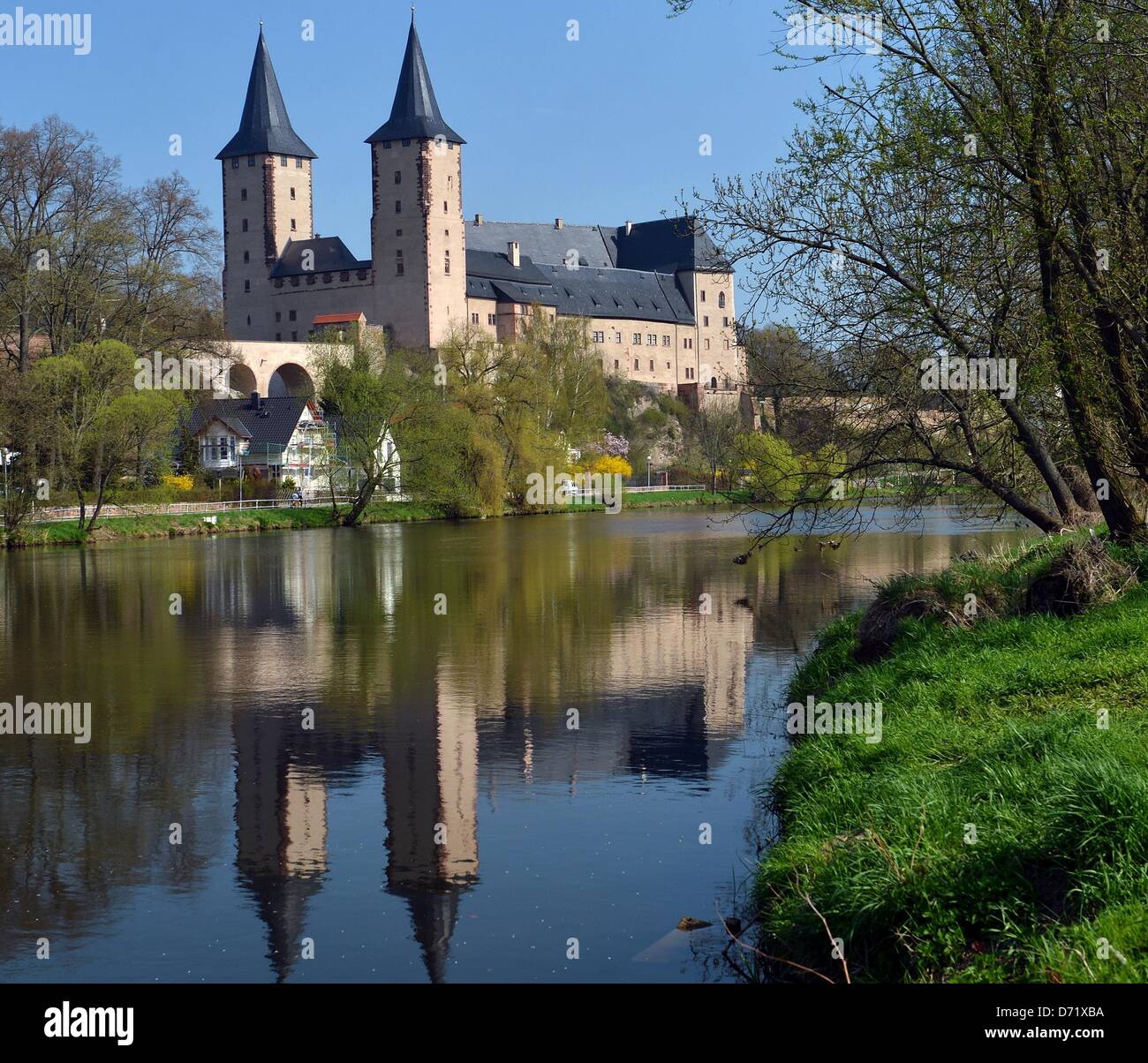 The two towers of Rochlitz Castle are reflected in the Mulde River in ...