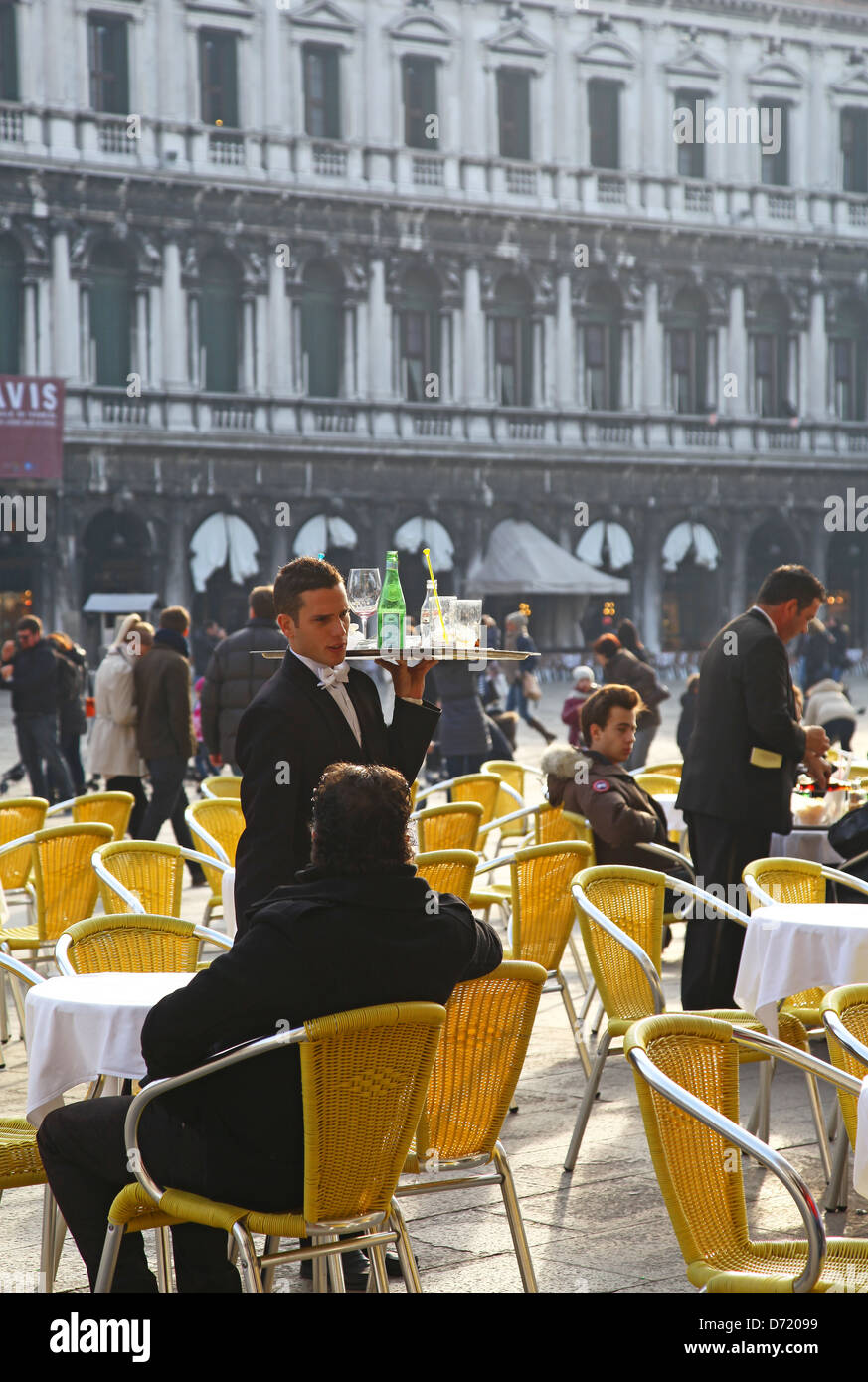 A waiter serving customers at one of the outdoor pavement cafes in St ...
