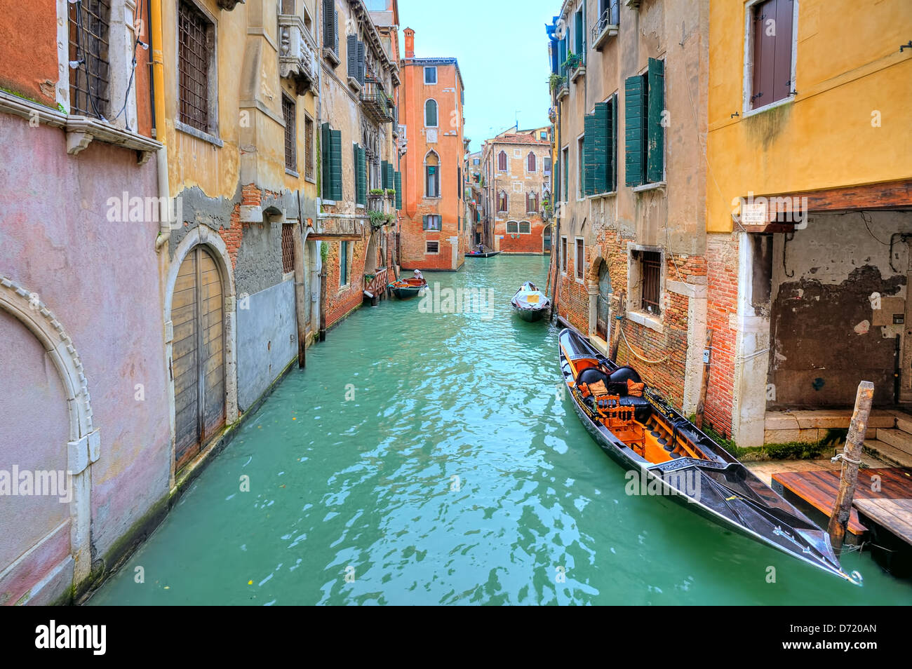 Gondola floats on small canal among old colorful houses in Venice ...