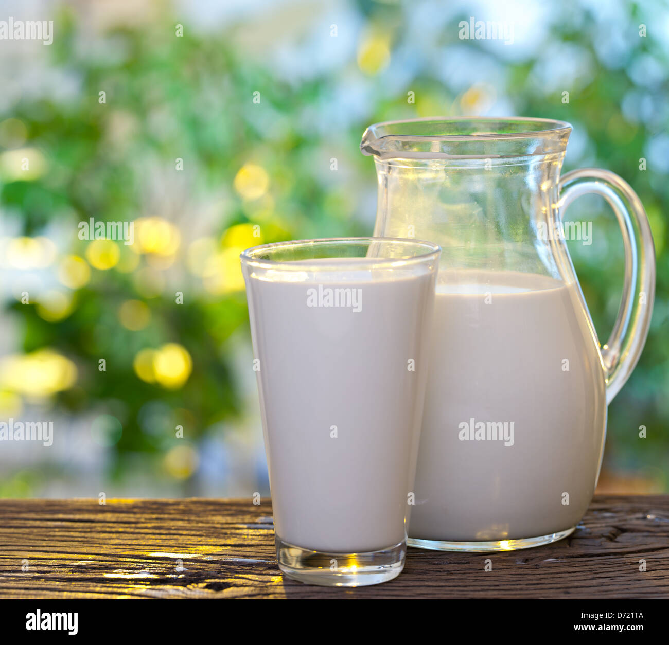 Milk in jar and glass on the old wooden table on a outdoor setting ...