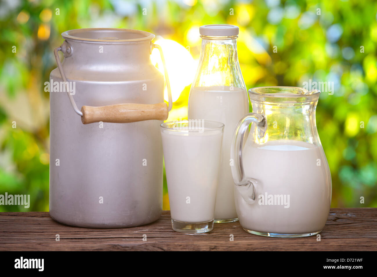 Milk in various dishes on the old wooden table in an outdoor setting ...