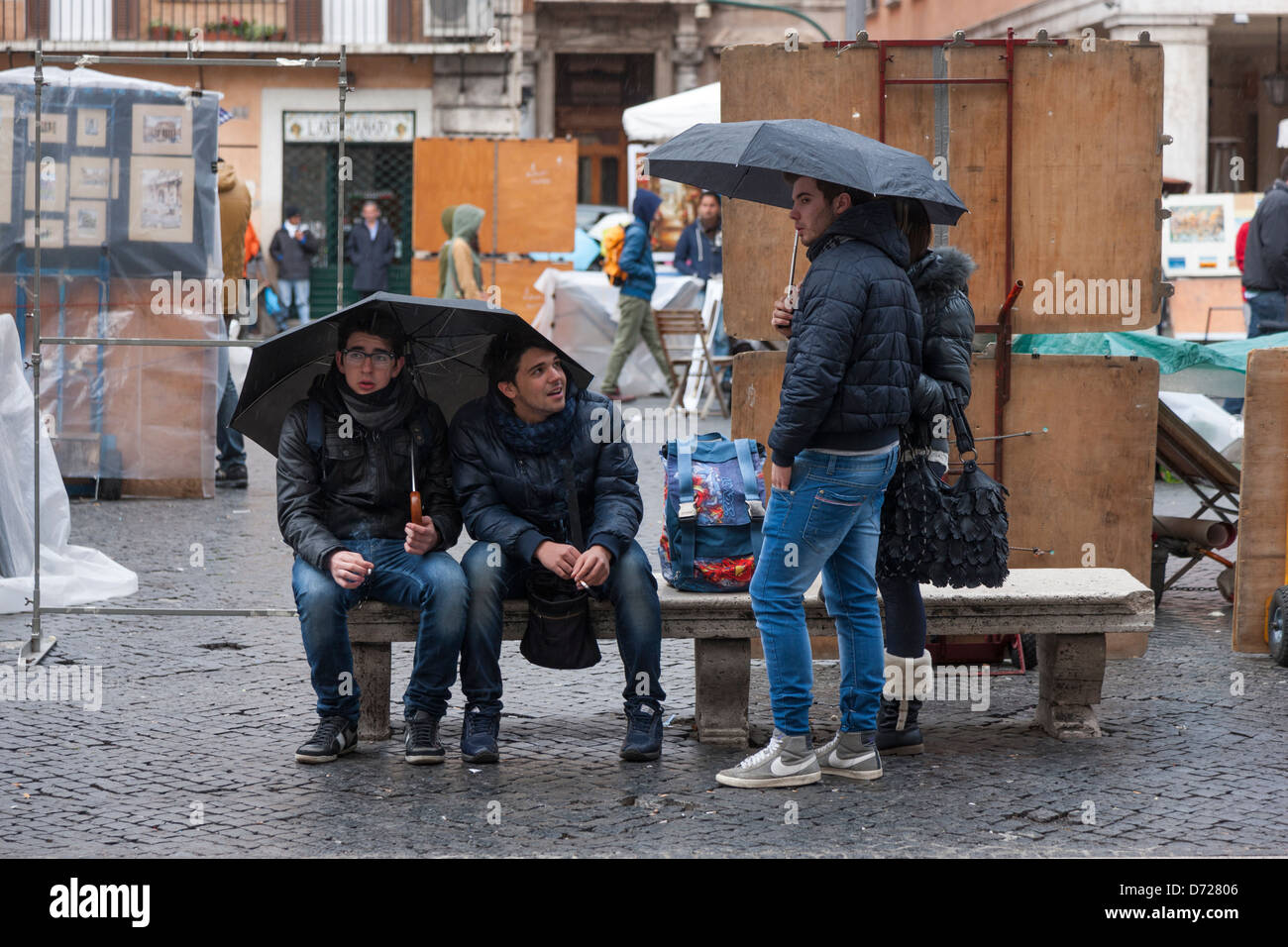 People sheltering from the rain under cheap umbrellas in Piazza Navona ...