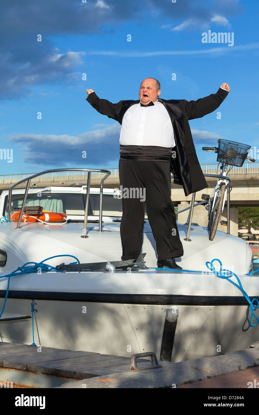 Overweight man in tuxedo standing on the deck of a luxury pleasure boat ...