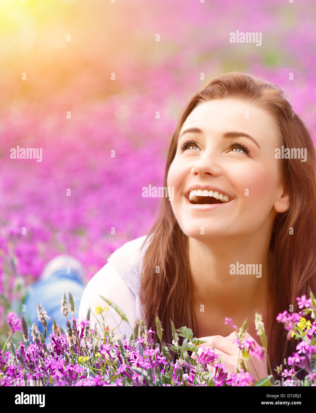 Closeup portrait of beautiful female laying down in fresh pink floral ...