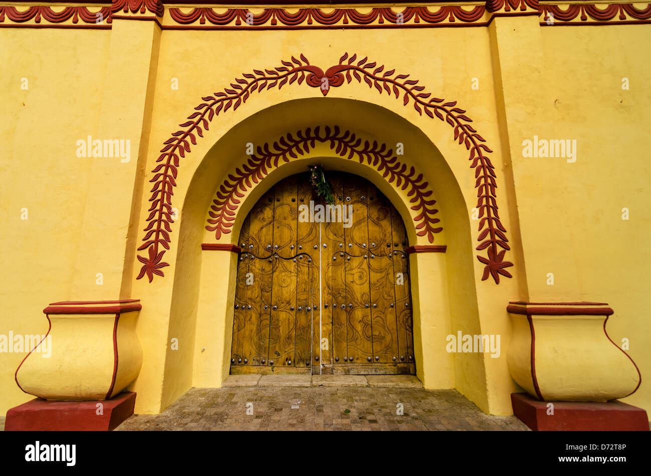 Intricate artwork of the entrance to a yellow and red church in Mexico ...
