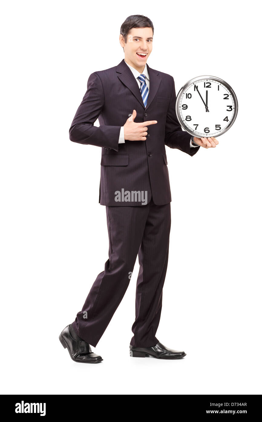 Full length portrait of a young man in suit pointing on a clock ...