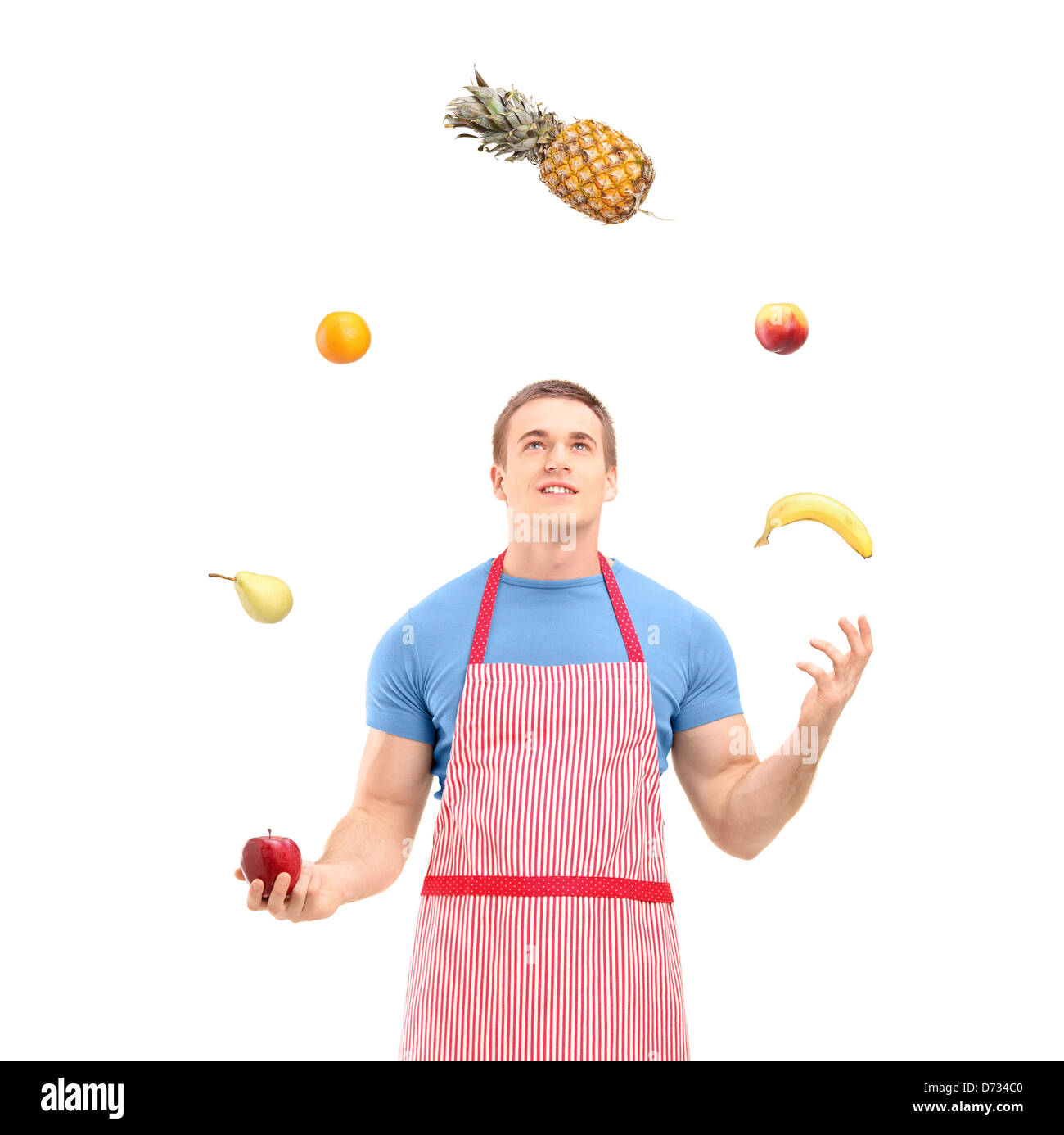 Young man in apron juggling with fruits, isolated on white background ...