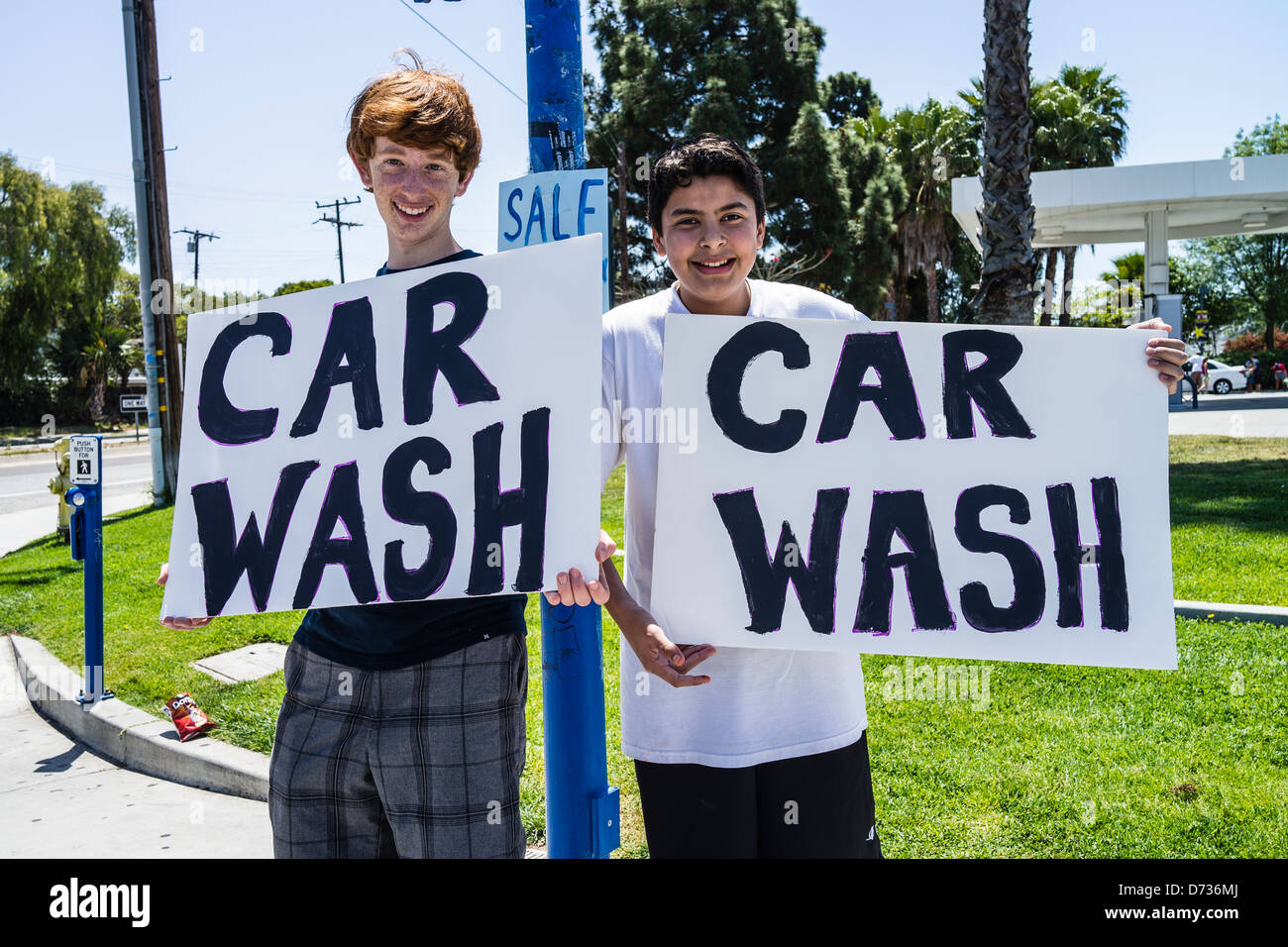 Two high school students, trying to get business, hold up signs that ...