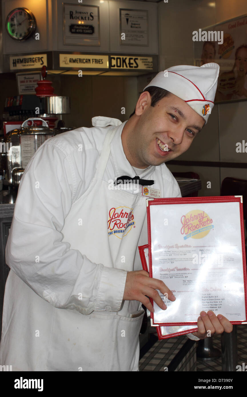 An old retro diner with the waiter in traditional uniform holding a ...