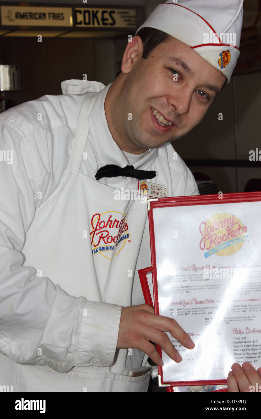 An old retro diner with the waiter in traditional uniform holding a ...