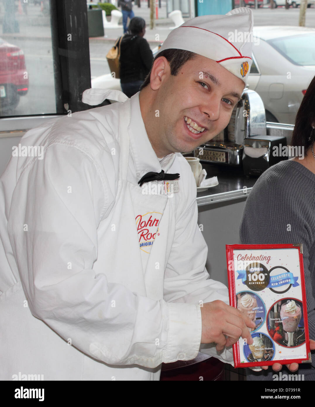 An old retro diner with the waiter in traditional uniform holding a ...