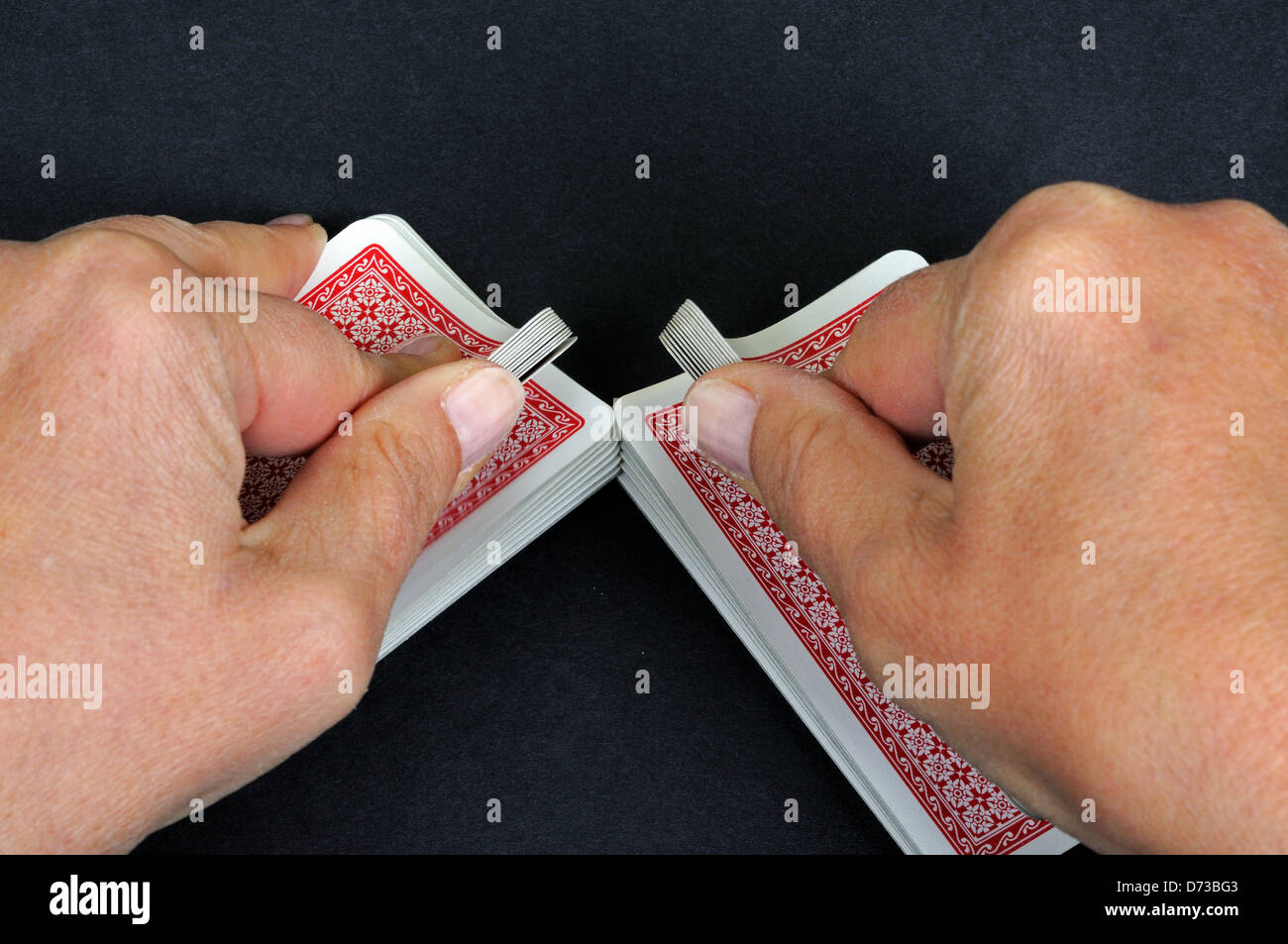 Woman shuffling a pack of playing cards against a black background ...
