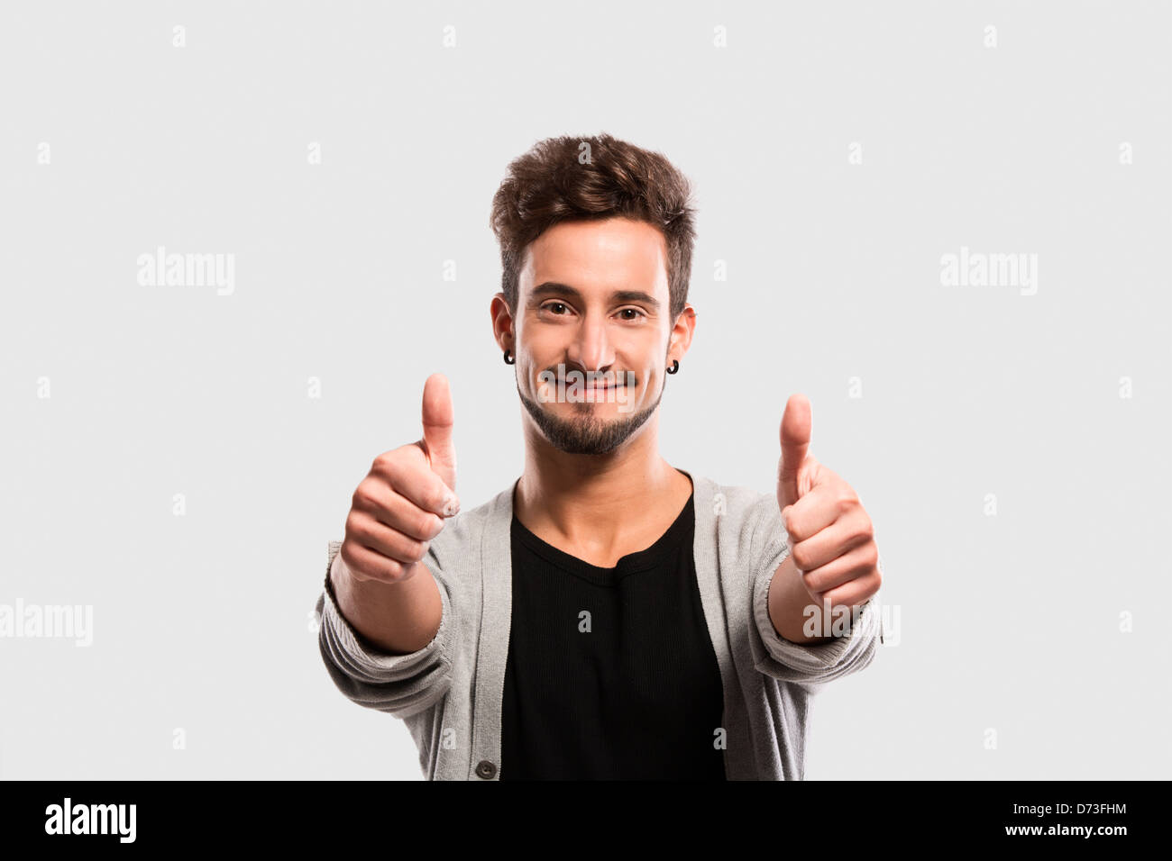 Handsome young man with thumbs up, over a gray background Stock Photo ...