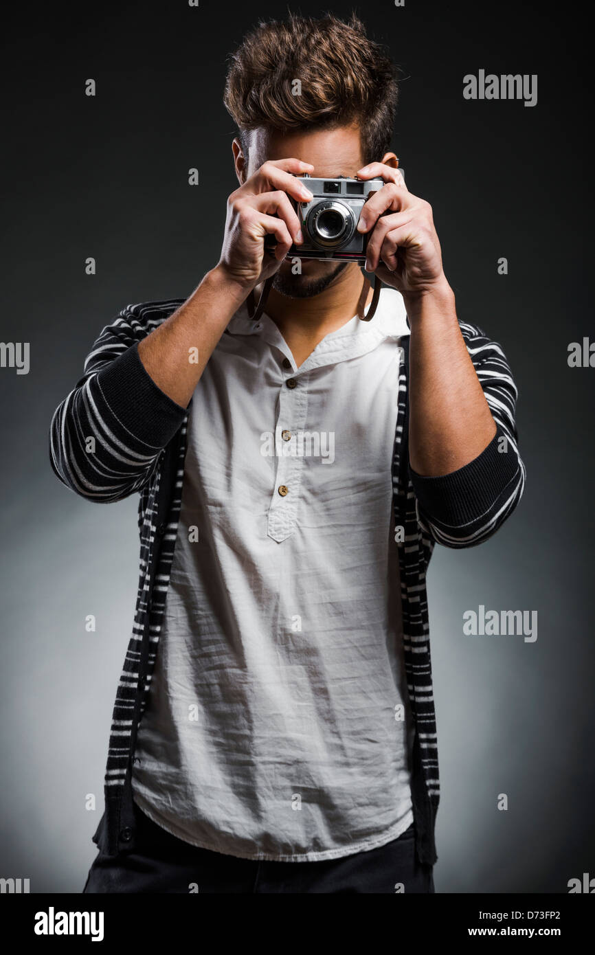 Studio portrait of a fashion young man posing with a old photographic ...