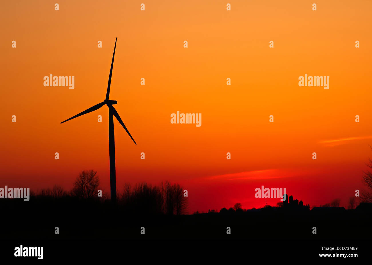 Wind farm at sunset with barns and silos in the twilight background ...