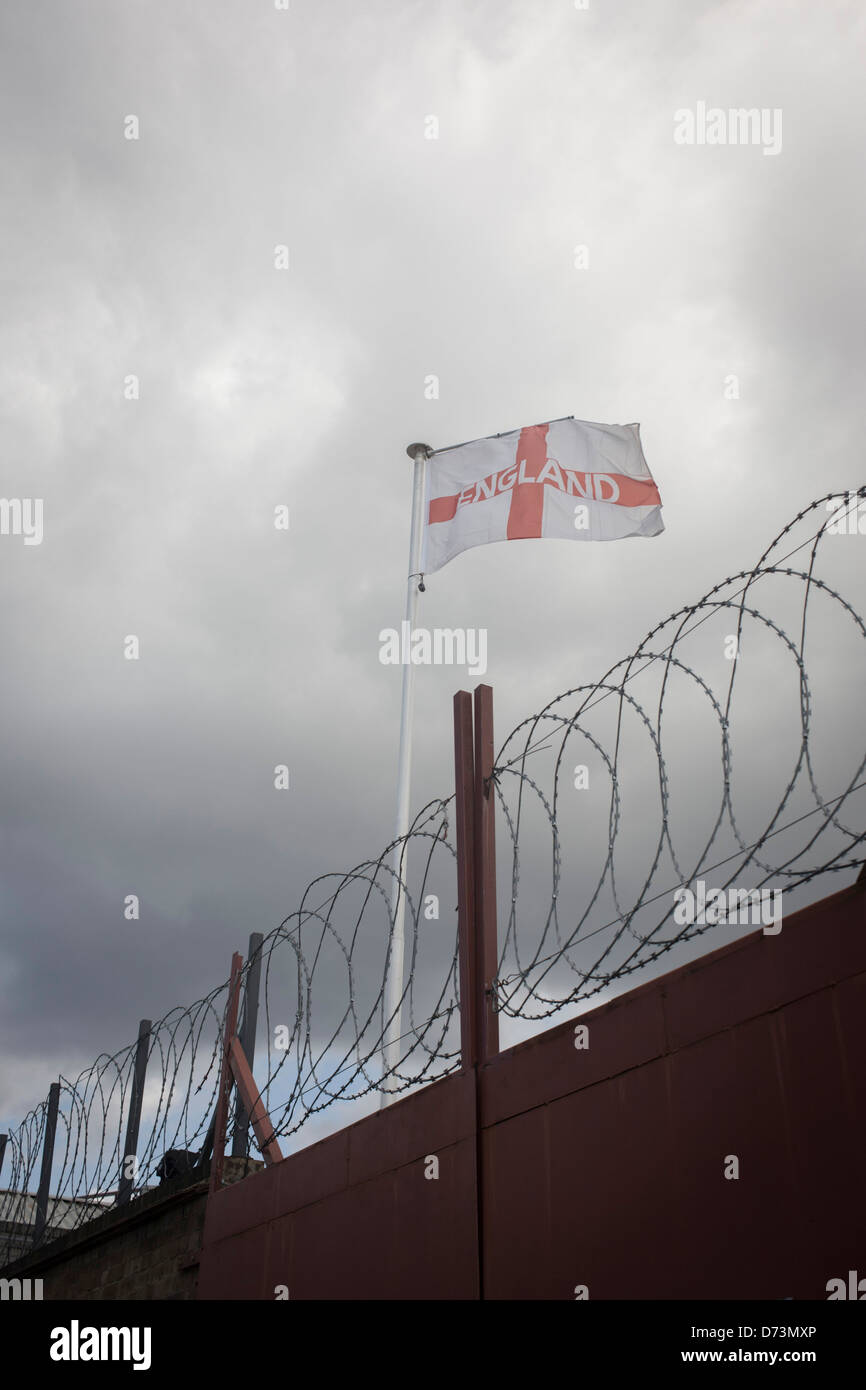 With coils of barded security wire beneath, a sad-looking English flag ...