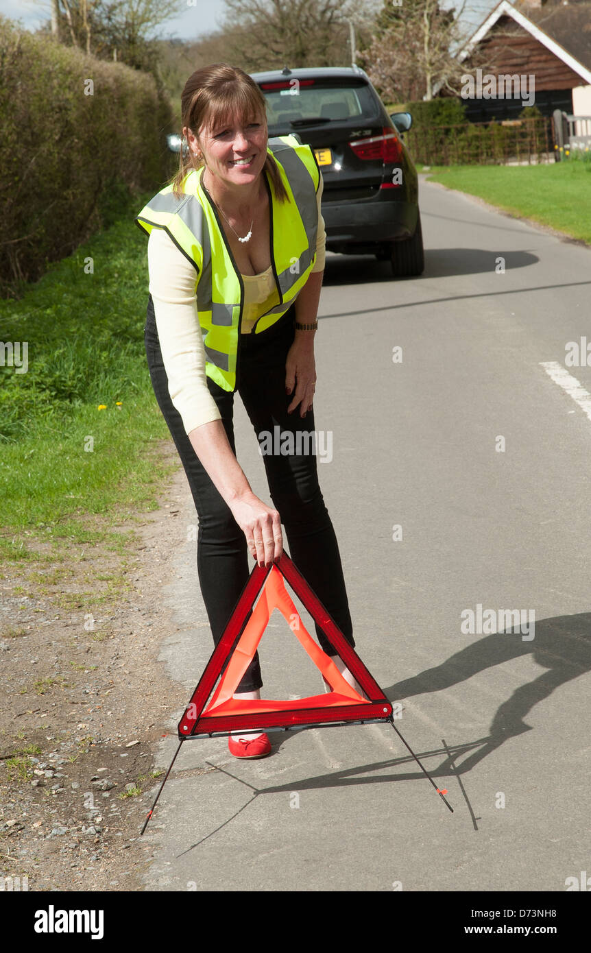 Female motorist putting out a red warning triangle behind her car Stock ...