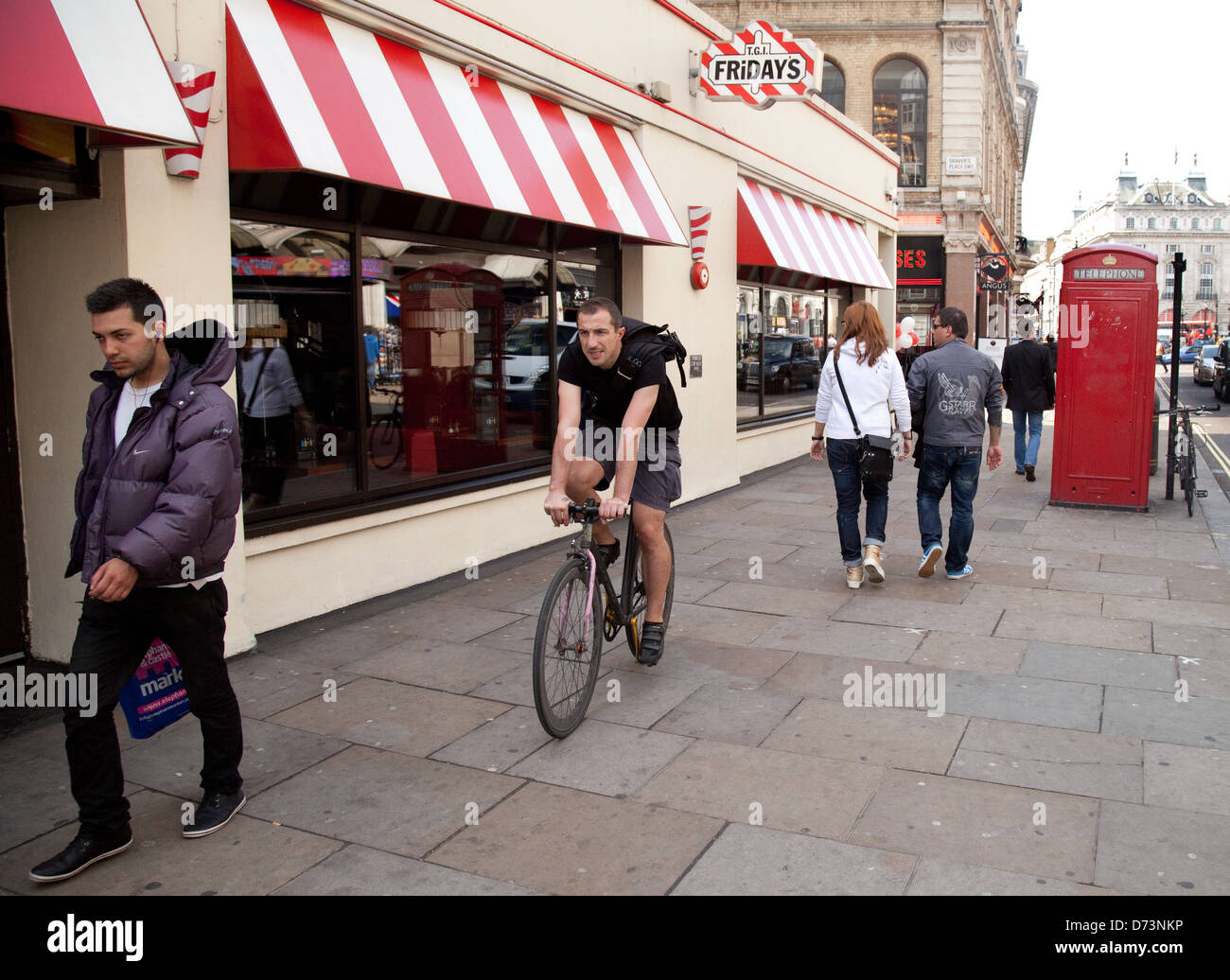 A man riding a bicycle, cycling on the pavement, Coventry Street ...