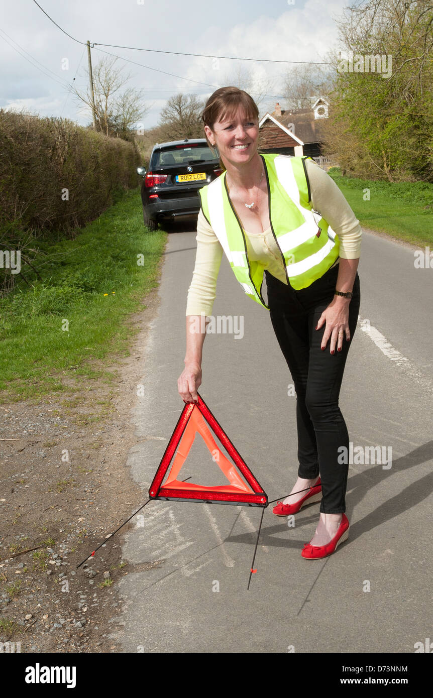 Female motorist putting out a red warning triangle behind her car Stock ...