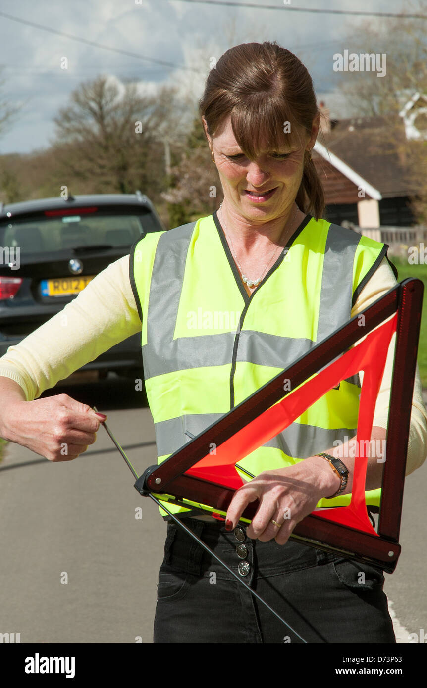 Female motorist putting out a red warning triangle behind her car Stock ...