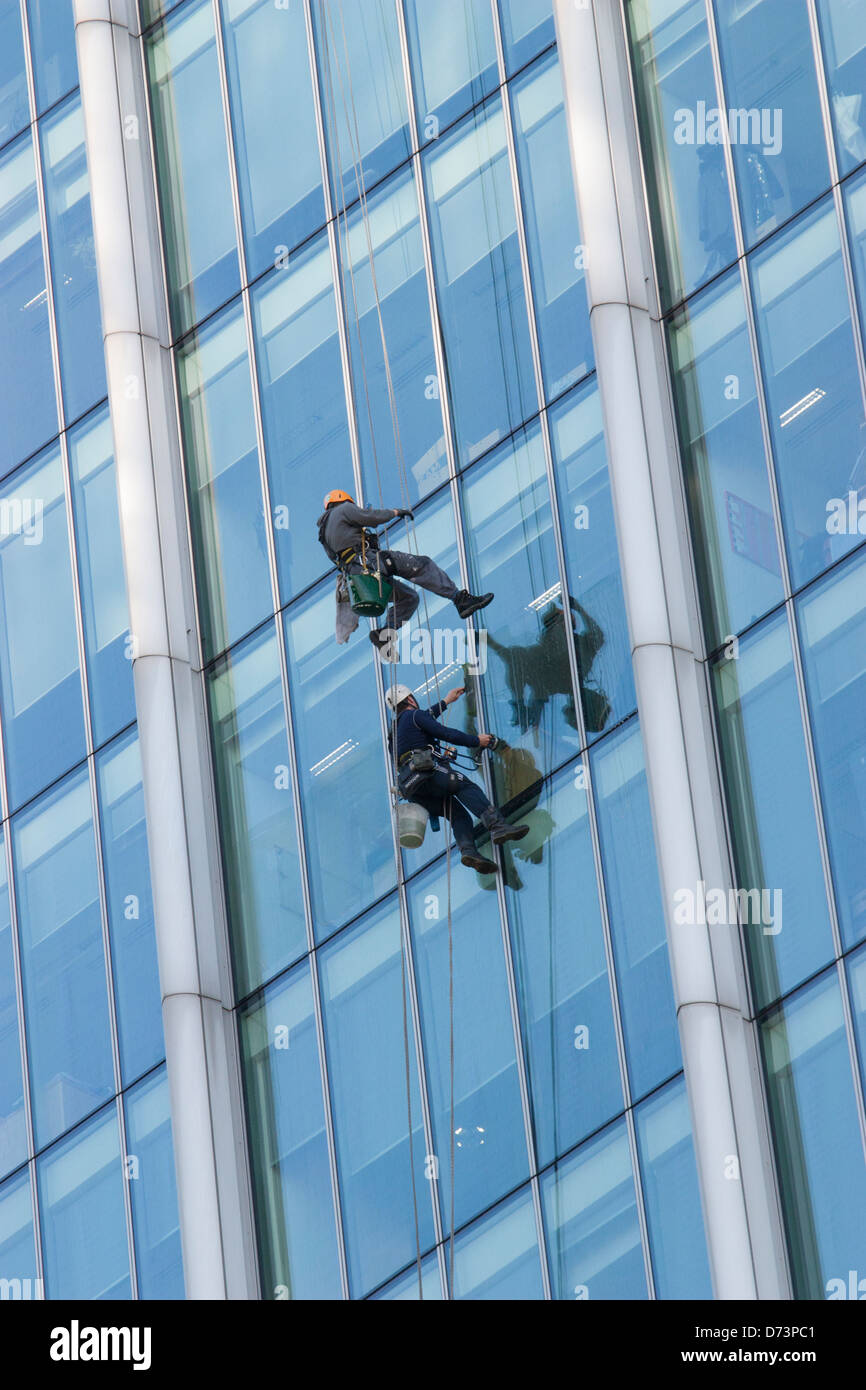 Window cleaners suspended on rigs clean the glass facade of CityPoint ...