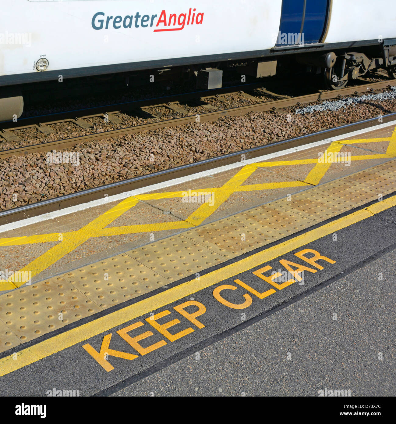 Warning sign on station platform edge with non slip paving and yellow ...