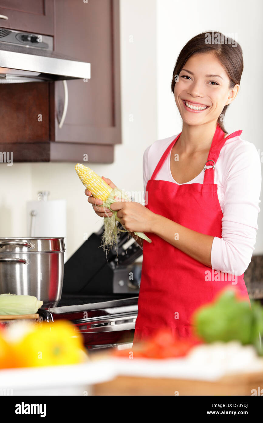 Kitchen woman making food smiling happy in apron peeling corn ...