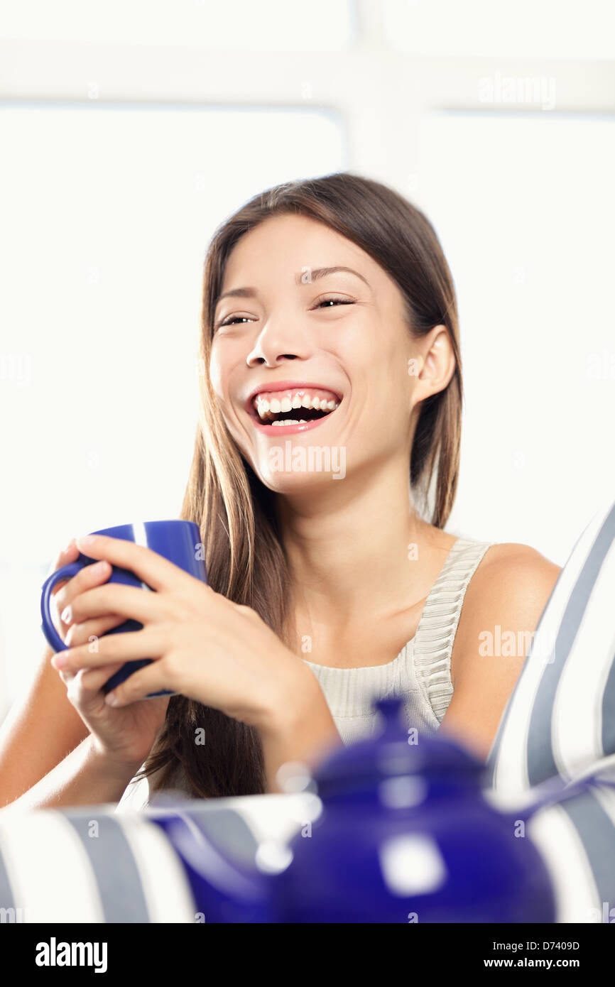 Woman laughing drinking tea, relaxing at home in couch. Smiling happy ...