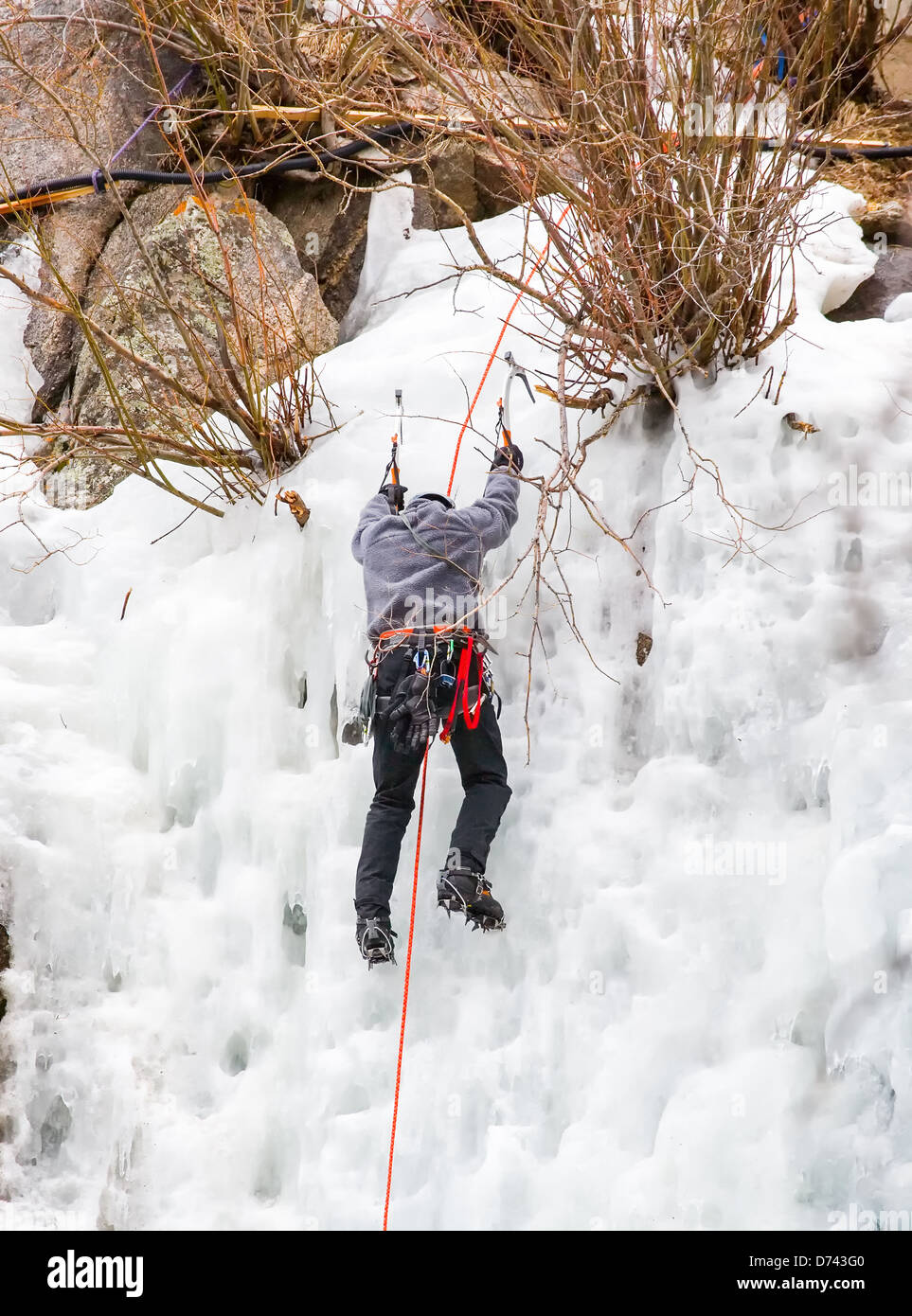A Caucasian male ice climber struggles to ascend a waterfall Stock ...