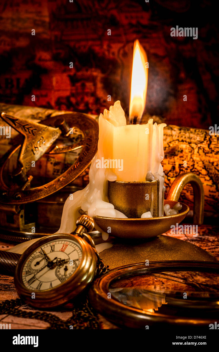 Vintage compass, pocket watch lie on an old ancient map with a lit ...