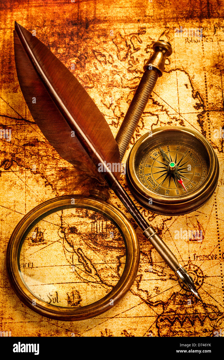 Vintage magnifying glass, compass and goose quill pen lying on an old ...