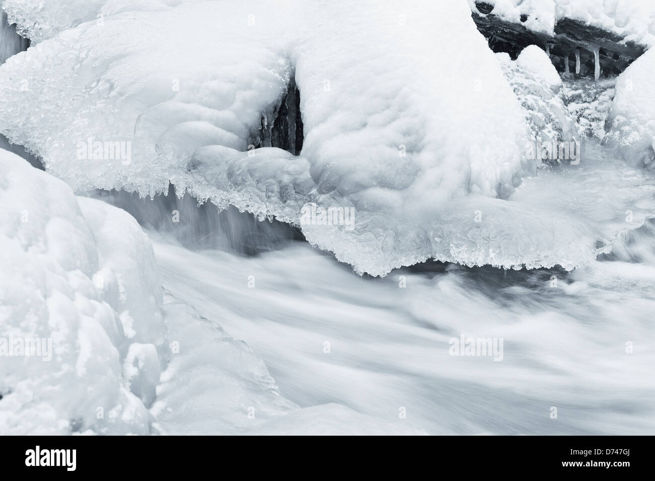 Melt water streaming through and over rocks covered in snow and ice ...