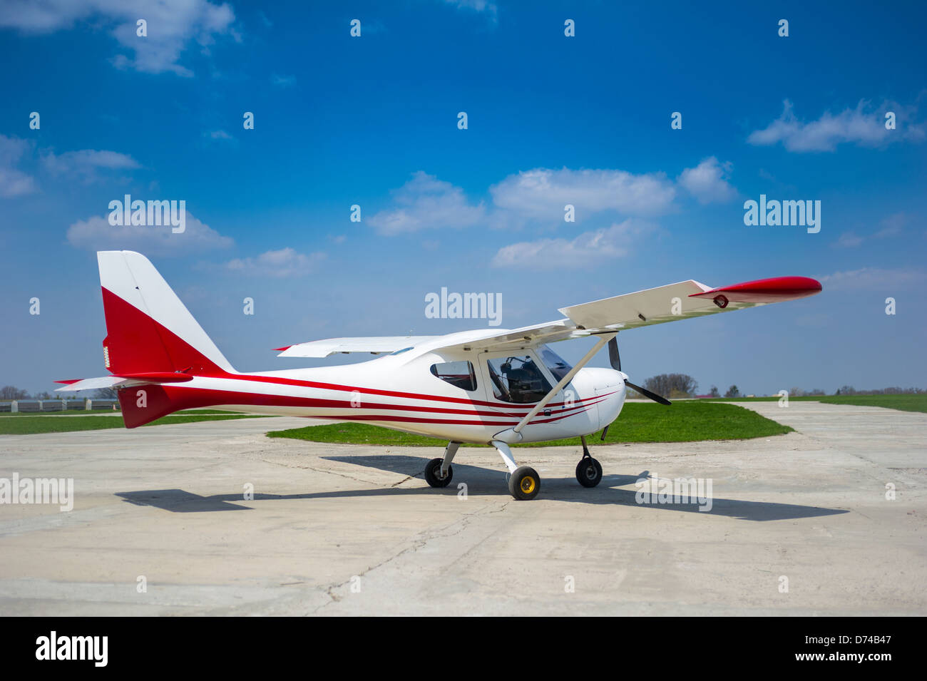 Single-engine sport aircraft ready to take off. Blue sky with clouds on ...