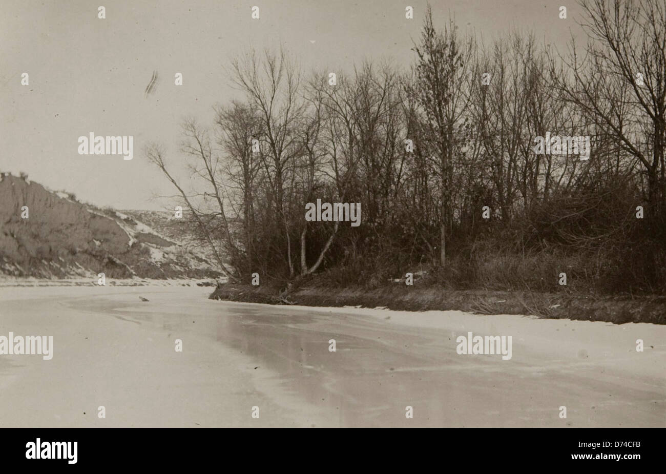 This photograph shows a frozen river landscape, captured with stark ...