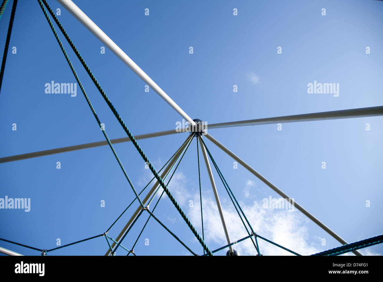 Detail of children's playground rope climbing frame against blue sky ...