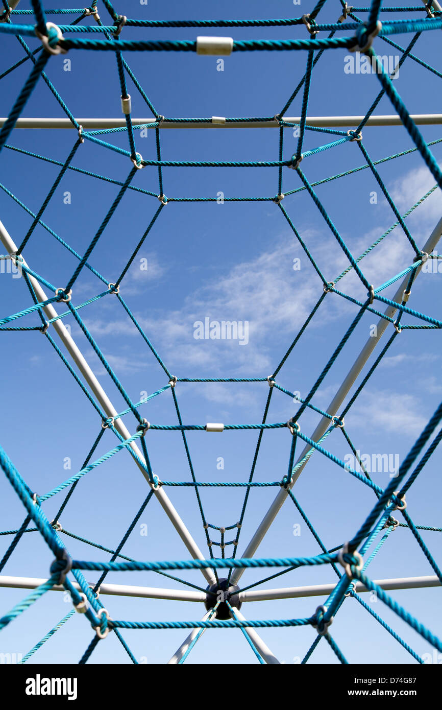 Detail of children's playground rope climbing frame against blue sky ...